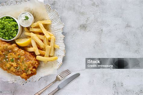 레몬 슬라이스 타르타르 소스 부드러운 완두콩 나이프와 포크 대리석 효과 배경 높은 보기 복사 공간과 함께 제공되는 기름칠 양피지가 있는 불규칙한 테두리가 있는 흰색 금색