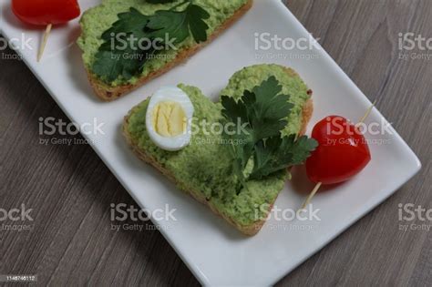 아침 식사 샌드위치 아보카도가 묻어 있는 하트 모양의 빵 슬라이스 삶은 메 추리 알 파 슬 리 토마토로 장식 되어 있습니다 흰색