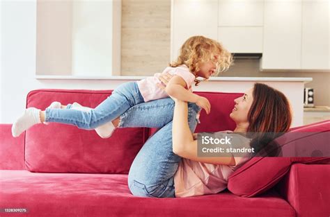 빨간 소파에 재미 젊은 어머니 와 그녀의 작은 딸 에 캐주얼 옷 함께 실내 에 집 2 3 살에 대한 스톡 사진 및 기타 이미지