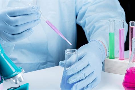 A Laboratory Test Tube With A Green Solution In A Mans Hand Is Heated