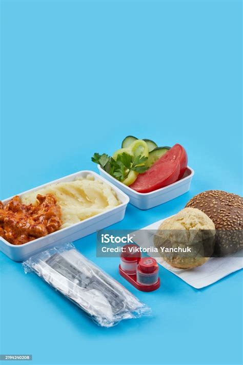 부드러운 파란색 배경에 닫으면 일회용 식기 비행기 음식 스낵 일회용 세트 소금과 후추 커틀릿을 곁들인 삶은 감자 베이글 롤빵 오이와 토마토가 있습니다 0명에 대한 스톡 사진