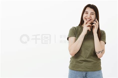 Wifi高清图片 女人与朋友进行随意搞笑的聊天，通过智能手机交谈，将手机放在耳边咯咯地笑，微笑着把手放在嘴边 产品实拍免费下载格式