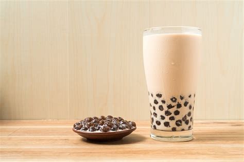 유리 잔의 진주 우유 차 와 나무 배경에 타 피 오카 볼의 접시 진주 밀크 티는 대만에서 가장 대표적인 음료입니다 대만 음식