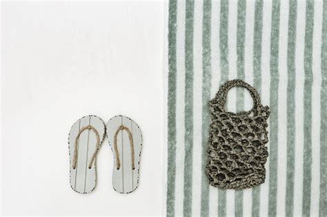 니트 비치 가방과 복사 공간 흰색 배경에 회색 플립 플롭 비치 타월 스트라이프 패턴입니다 해변 휴가의 개념입니다 가방에 대한