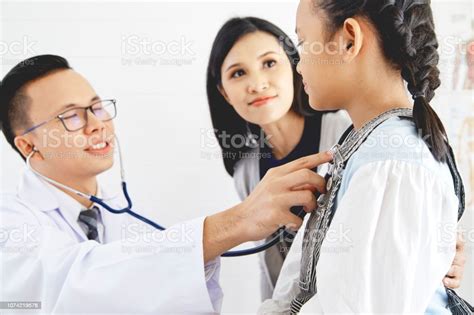 전문 의사 청진 기를 사용 하 여 병원 배경에서 그녀의 어머니와 아이 환자를 검사 하는 백색 외 투를 입고 가족에 대한 스톡