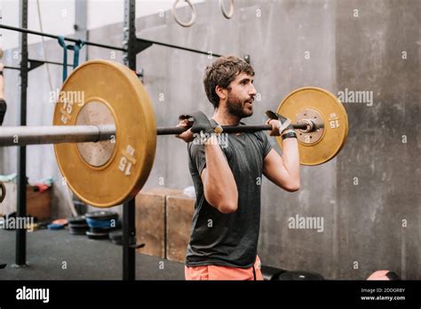 Side View Of Muscular Male Athlete Doing Clean And Jerk Exercise While Training In Modern