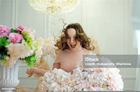 섬세한 분홍색 옷을 입은 소녀와 밝은 분홍색 방에서 꽃의 심장부와 함께 놀고 사진 스튜디오의 웨딩 살롱은 매우 멋지고 귀엽게