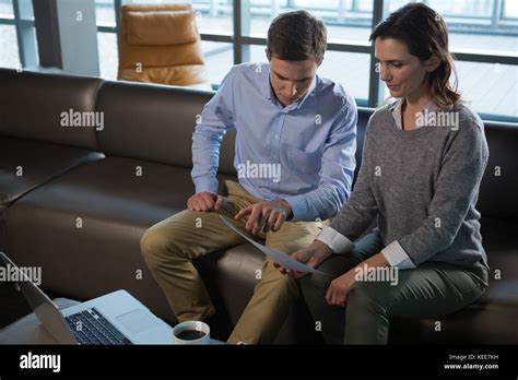 Male Executive And Female Executive Discussing Over Document In Futuristic Office Stock Photo