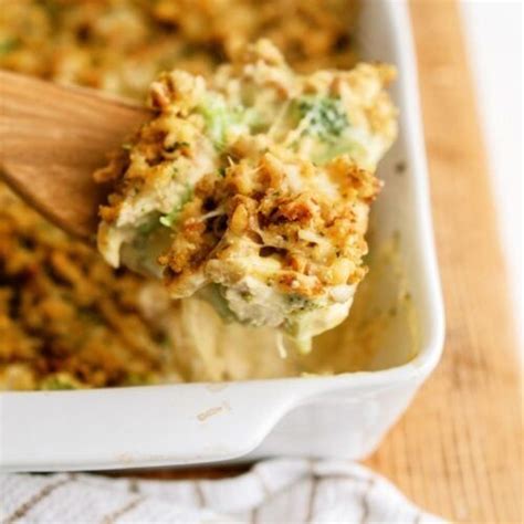 A Casserole Dish With Broccoli In It And A Wooden Spatula