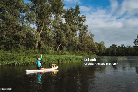 여자는 강가의 Sup 보드에 떠 기쁜 미소를 지으며 카메라를 향해 손을 흔들고 남자는 잔잔한 물 위에서 혼자 뗏목을 타고 손으로 인사하고 장비로 패들 보드를 한다 35 39