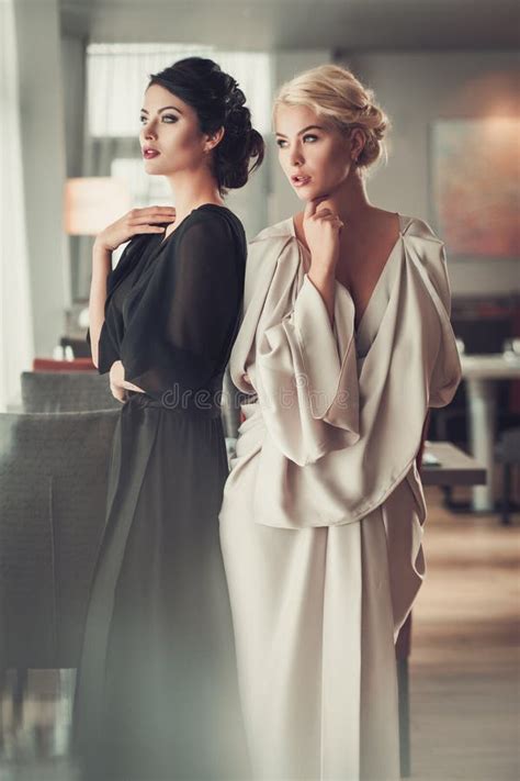 Two Charming Ladies In Elegant Evening Dresses In Restaurant Stock