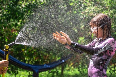 Una Niña Divertida Jugando Con Una Manguera De Jardín En El Patio