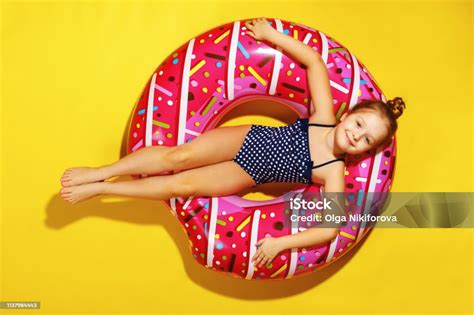 도넛 팽창 식 원에 누워 수영복 정장에 작은 아이 소녀 노란색 배경입니다 평면도 아이에 대한 스톡 사진 및 기타 이미지 아이