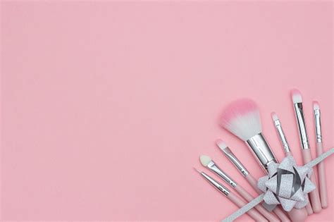 파스텔 핑크 배경에 메이크업 브러시와 리본 뱀의 활의 집합입니다 텍스트 또는 디자인에 대 한 템플릿입니다 평면도 복사 공간 0