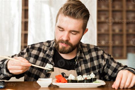 Man Eating Sushi Rolls Using Bamboo Sticks In A Restaurant Japanese