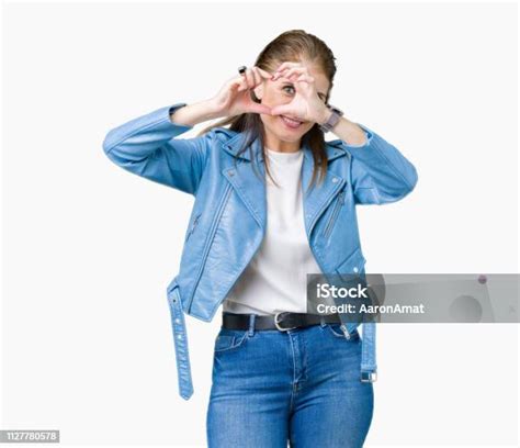 아름 다운 중간 나이 성숙한 여성 입고 패션 가죽 자 켓 격리 된 배경 하 고 손과 손가락으로 심장 모양 웃는 기호를 통해 찾고 가죽에 대한 스톡 사진 및 기타 이미지