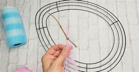 An Egg Shaped Wire Wreath A Roll Of Blue Decorative Mesh And A Hand
