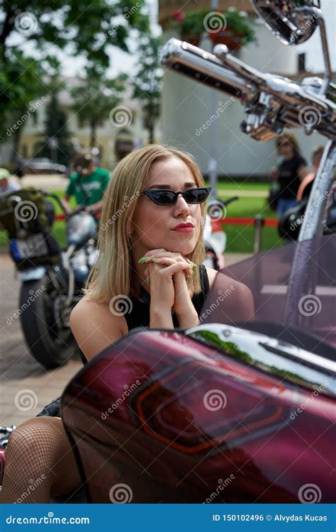 Молодая сексуальная женщина сидя на мотоцикле Красивая девушка представляет на мотоцикле