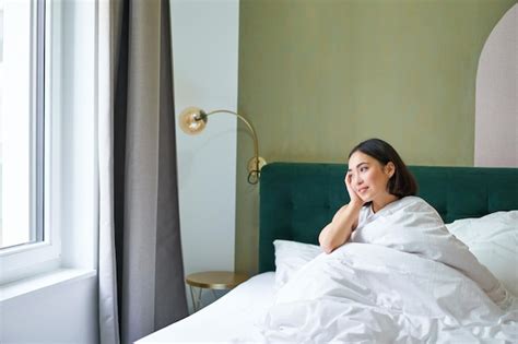 Uma Feliz Mulher Coreana Acorda Em Seu Quarto De Hotel Deitada Na Cama