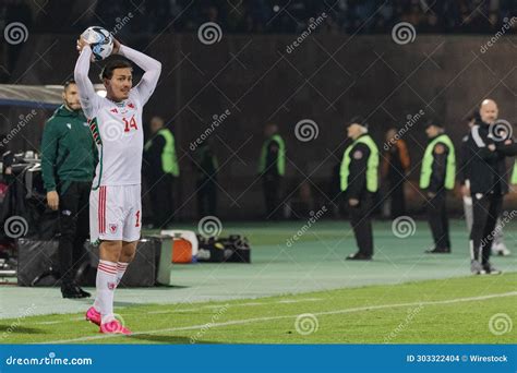 A Male Soccer Player Wearing A White And Green Uniform Standing On A