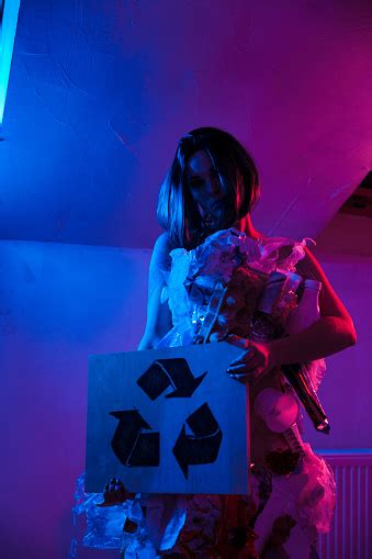 리사이클 사인 플라스틱과 골판지로 만든 쓰레기 드레스를 입고 웃는 여성 에코 파이터의 초상화는 오염 인식 개념에서 환경 청소