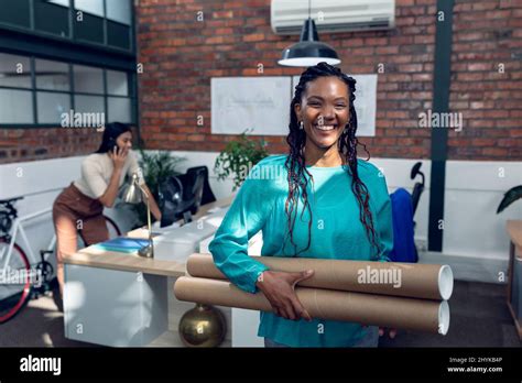 Portrait Of Smiling African American Young Female Architects Standing With Cardboard Blueprint