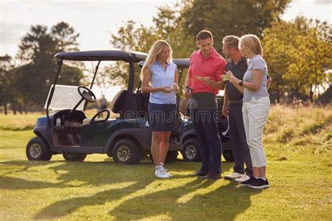 Mature And Mid Adult Couples Standing By Golf Buggy Checking Score Cards Together Stock Image