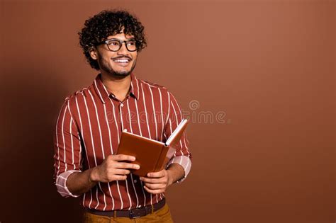 Portrait Of Nice Young Man Hold Book Look Empty Space Wear Striped