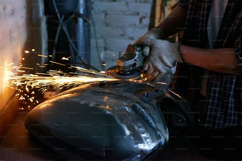 알아볼 수 없는 수리공 체크 셔츠를 입고 오토바이 연료 탱크 부품 사진 Unsplash의 어금니 이미지