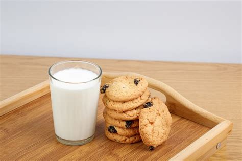 Premium Photo A Glass Of Milk And Cookies With Raisins On A Wooden Tray