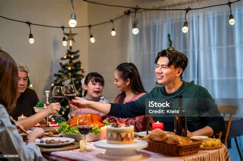 집에서 함께 크리스마스 파티를 축하하는 아시아 사랑스러운 가족 저녁 식사를하는 매력적인 부모와 친척 휴일 추수 감사절 식탁에서 크리스마스 이브를 축하하기 위해 와인 한 잔을