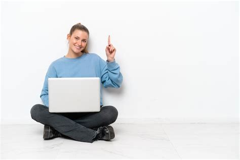Jovem mulher sentada no chão um laptop mostrando e levantando um
