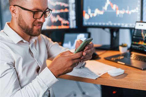 손에 전화로 정장 옷을 입은 젊은 사업가가 여러 개의 스크린으로 사무실에 있습니다 25 29세에 대한 스톡 사진 및 기타 이미지 25 29세 그래프 금융 Istock