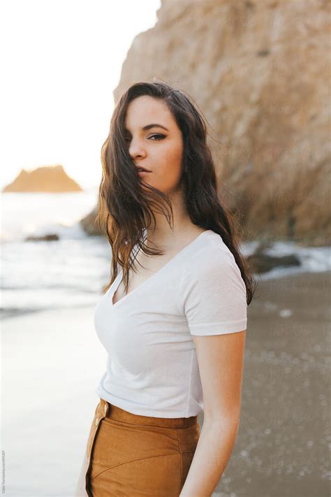 A Cute Girl Poses On The Beach For A Photograph By Stocksy