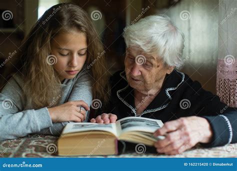 Κοριτσάκι με την γριά γιαγιά της να διαβάζει ένα βιβλίο Στοκ Εικόνες εικόνα από Lifestyle