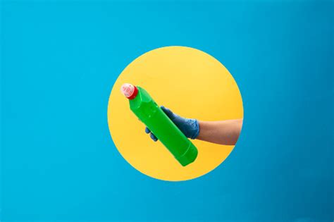 파란색과 노란색 종이 배경에 세제 병을 들고 파란색 의료 장갑에 손을 Covid 19에 대한 스톡 사진 및 기타 이미지