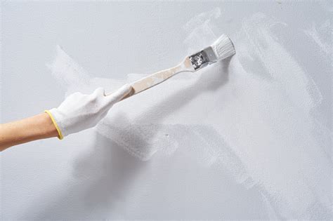 흰색 장갑을 낀 손은 흰 페인트 색상으로 물거품을 잡고 파란색 벽을 페인트합니다 Diy에 대한 스톡 사진 및 기타 이미지