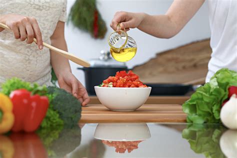 4 개의 인간 손 클로즈업 부엌에서 요리는 신선한 샐러드를 준비 하는 동안 재미는 친구 채식 건강 한 식사와 우정 개념 가까운에