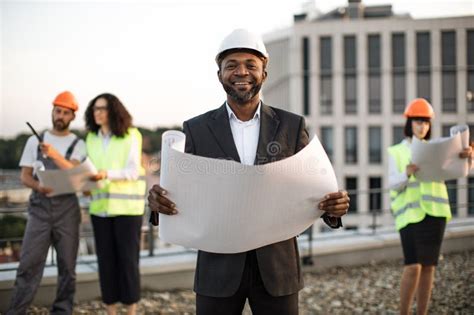 Investor Posing At Camera While Colleagues Inspecting Object Stock