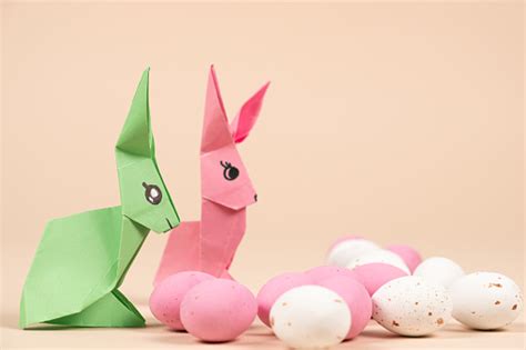 두 개의 종이 종이 접기 토끼와 베이지 색 배경에 부활절 달걀 부활절을위한 자신의 손으로 공예품 3가지 개체에 대한 스톡 사진