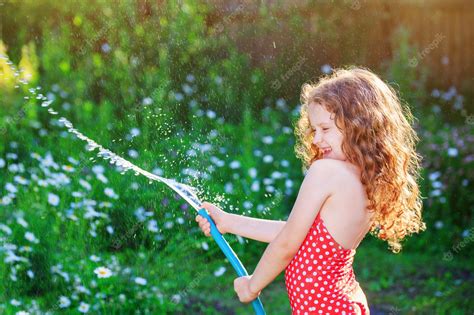 Niña Jugando Con Una Manguera De Jardín Foto Premium