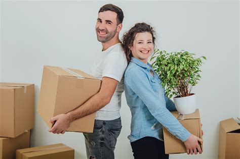 행복한 아내와 남편은 판지 상자를 들고 뒤로 서서 새 아파트로 이사하는 것에 매우 만족하는 미소를 지었습니다 2명에 대한 스톡 사진 및 기타 이미지 Istock