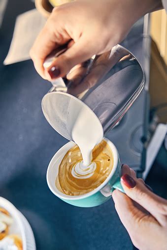 카페 컨셉의 전문 서비스 커피 하우스 바리스타 카페 라떼 아트 만들기 신선한 만든 커피 한 잔에 우유를 붓는다 우유와 커피 톤