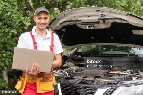 정비사 남자는 전체 작업 유니폼에 워크샵 차고 지원 서비스에서 도구 장비를 사용하여 자동차 엔진 자동차 차량 부품 수리 튜닝 수리를 검사하는 노트북 컴퓨터를 사용하여