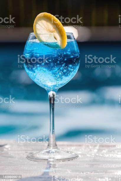 맛있는 블루 칵테일 블루 라군과 수영장 배경에 노란색 레몬 한 잔 알코올 칵테일 Curacao 리큐어 얼음 조각 및 레몬 조각을