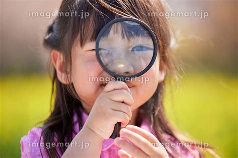 虫眼鏡を持つ日本人の女の子の写真素材 イメージマート