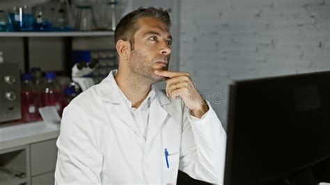 Cheerful Young Hispanic Scientist At Lab Thinking Up A Smart Idea