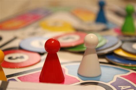 Red And White Pawns On A Game Board With Multiple Cards On Top Stock