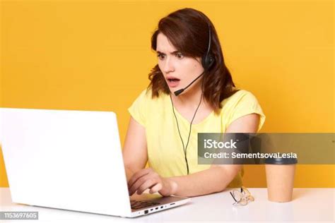 반 빼내야 사진 스튜디오에서 노란색 배경 위에 고립 된 laptopon 화면을 보고 열린 입으로 앉아있는 신경 젊은 여자 운영자