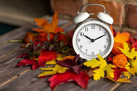 가을 겨울 시간 변경 개념 복고풍 알람 시계 밝은 노란색과 빨간색 잎 호두가있는 가을 구성 배경에 벽돌 벽입니다 아늑한 집 분위기 클로즈업 서머타임에 대한 스톡 사진 및